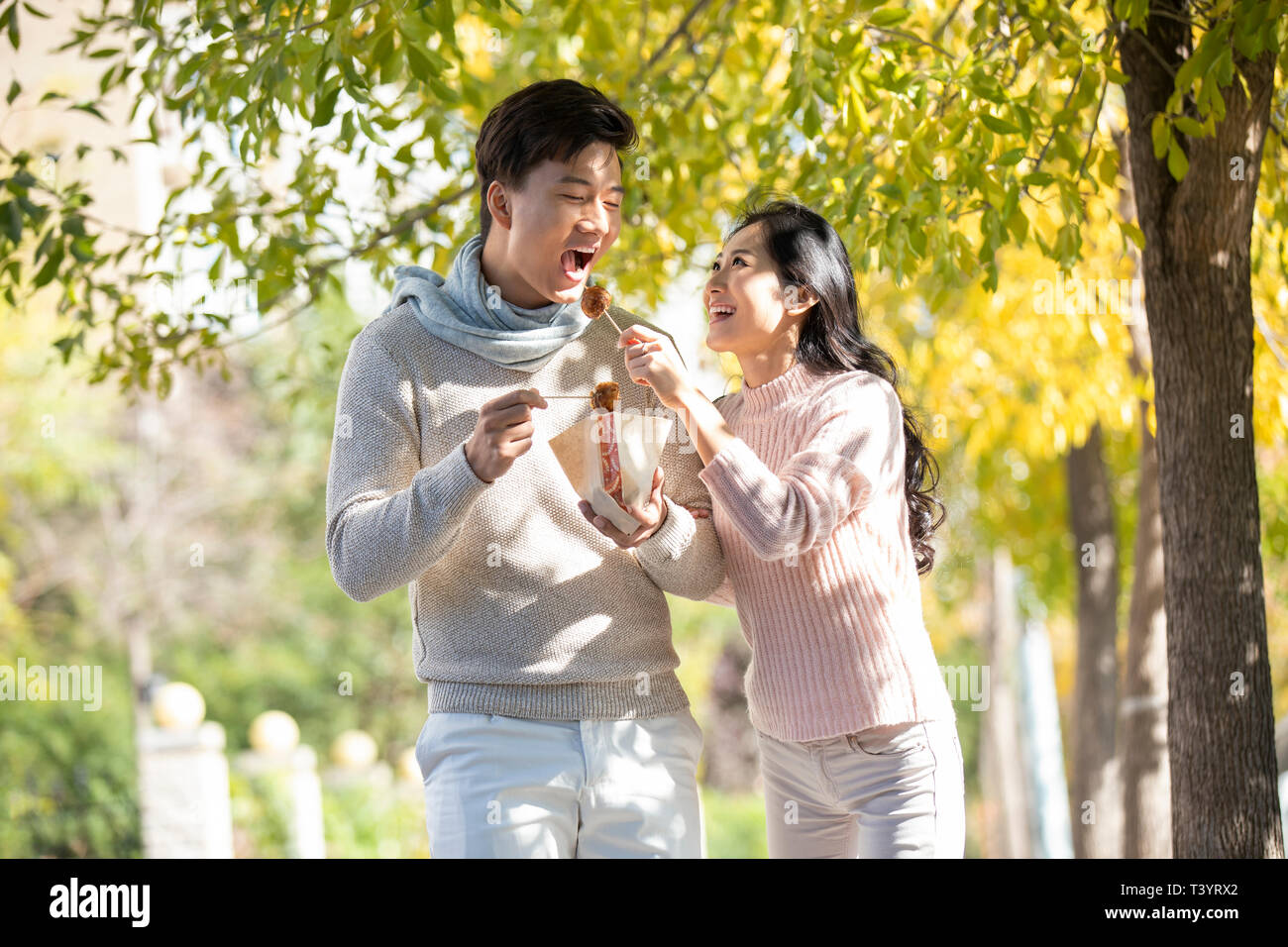Happy young couple eating snack Stock Photo - Alamy