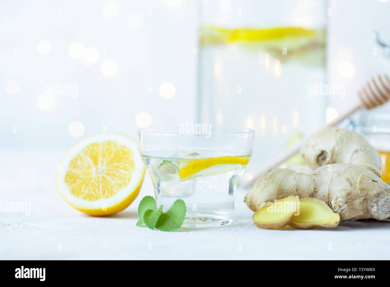 Healthy ginger drink in a cup. Ginger root, honey in a jar, lemon on a ...