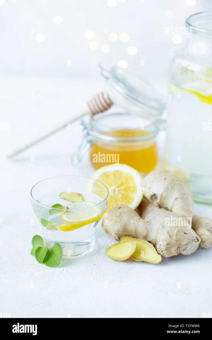 Healthy ginger drink in a cup. Ginger root, honey in a jar, lemon on a ...
