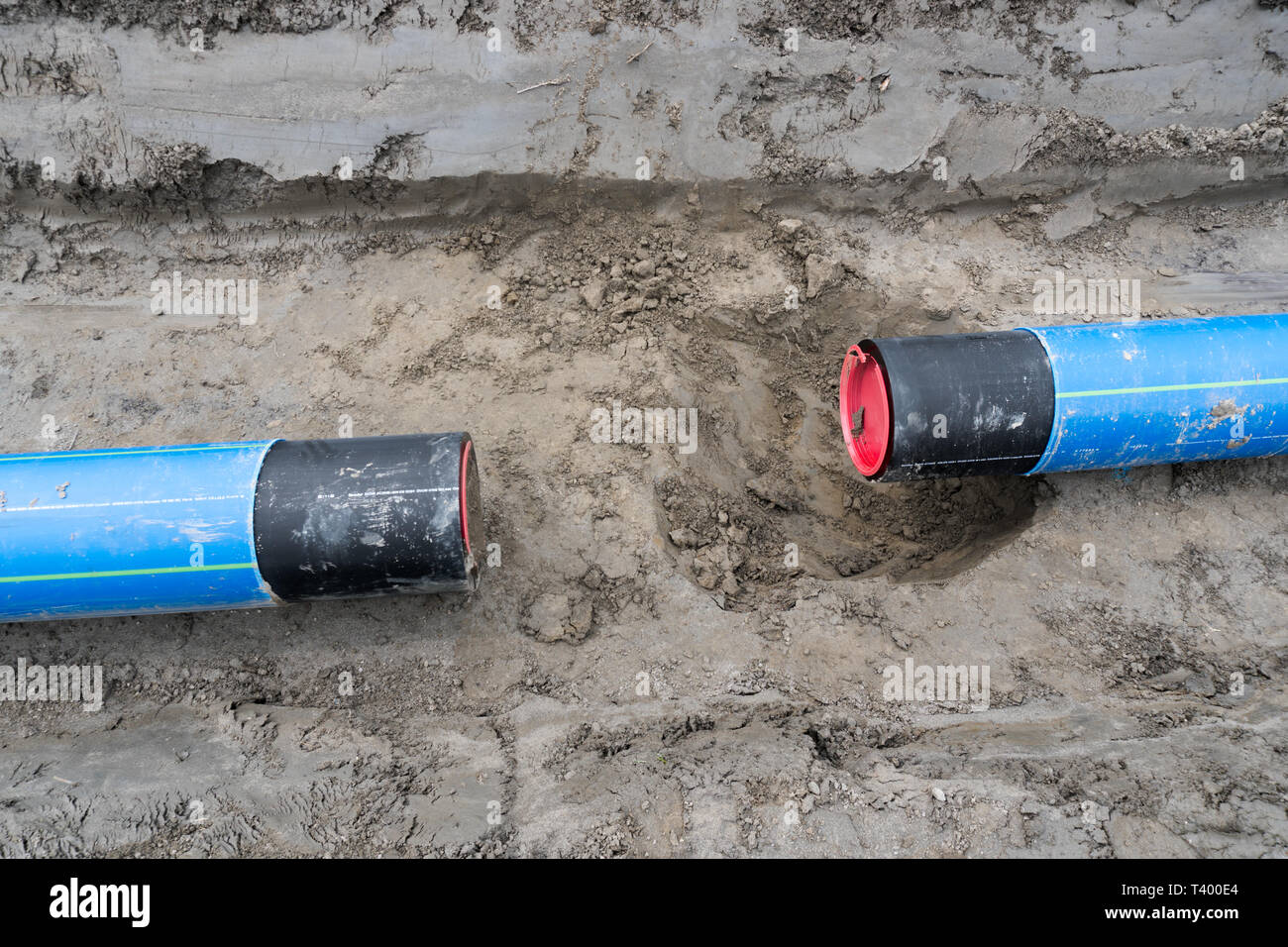 laying large industrial water pipes in an earth and dirt ditch for ...