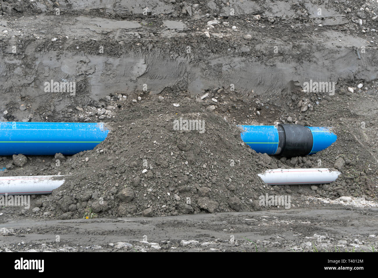 laying large industrial water pipes in an earth and dirt ditch for ...