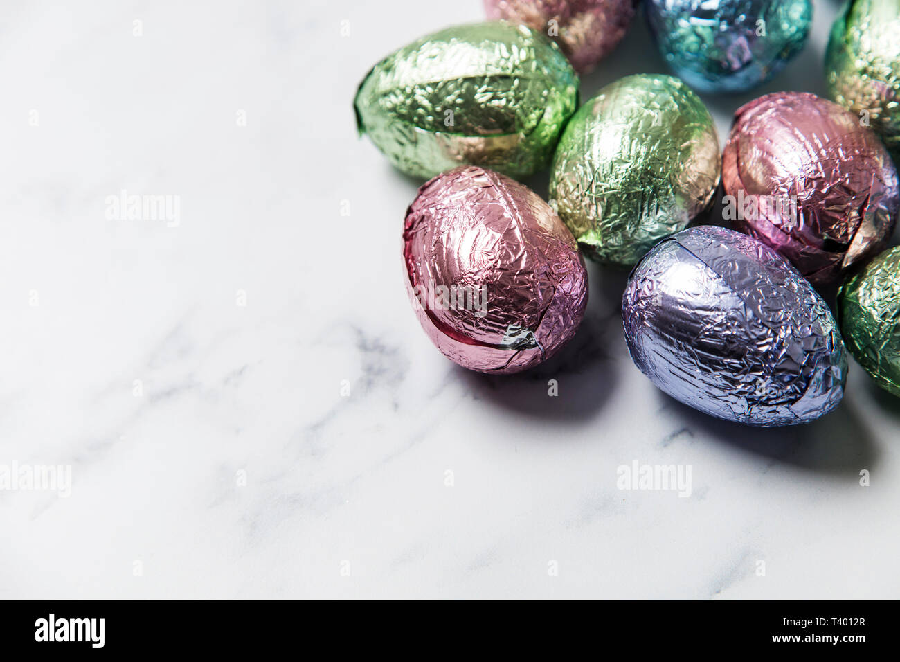 Easter egg chocolate treats wrapped in shiny coloured foil on marble ...