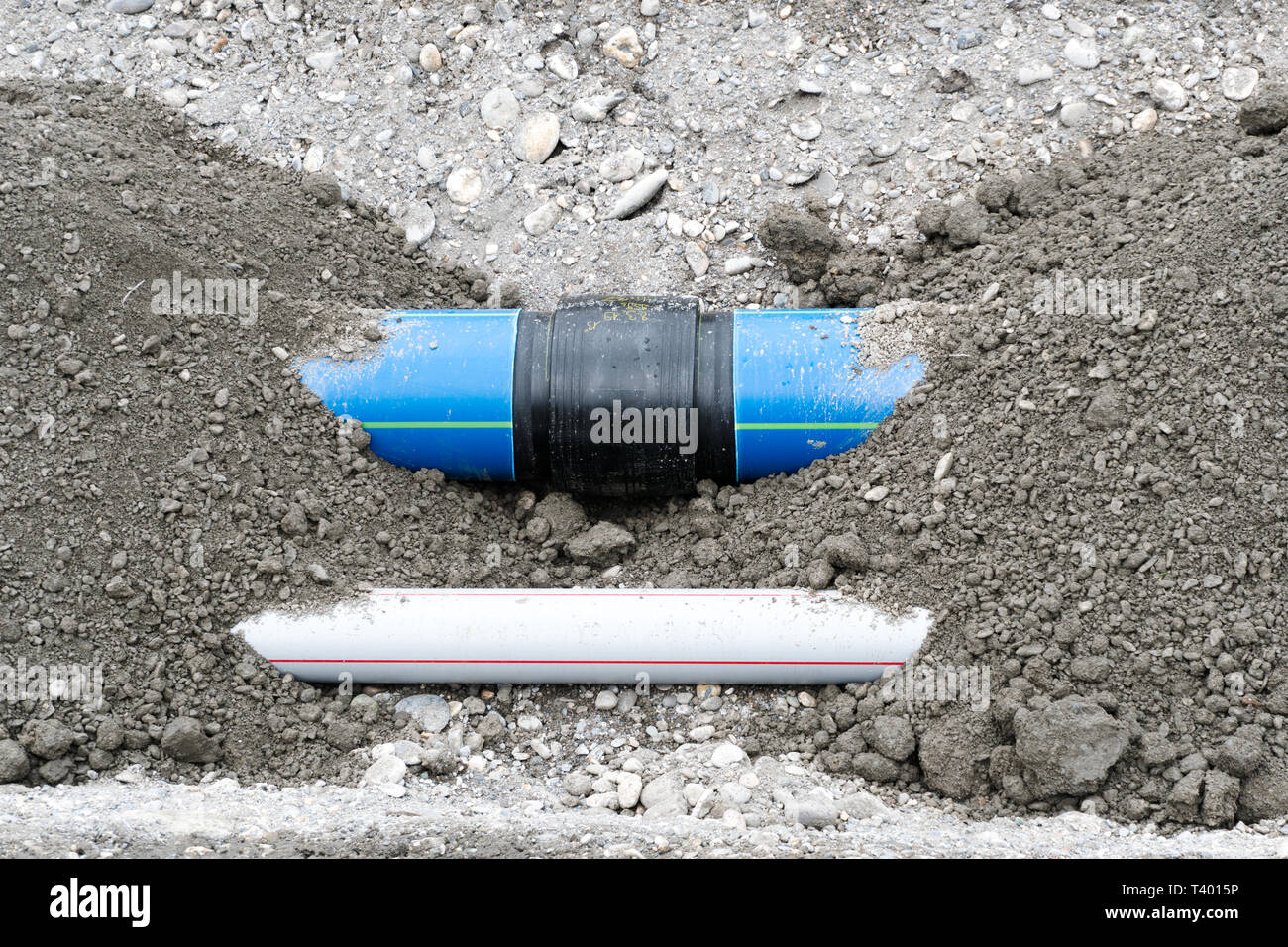 laying large industrial water pipes in an earth and dirt ditch for ...