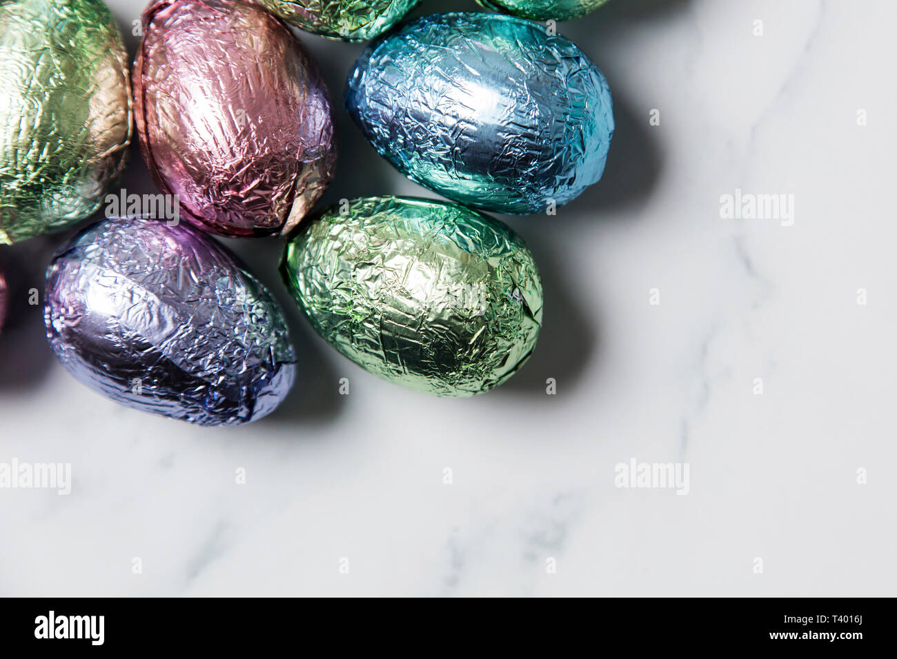 Easter egg chocolate treats wrapped in shiny coloured foil on marble ...