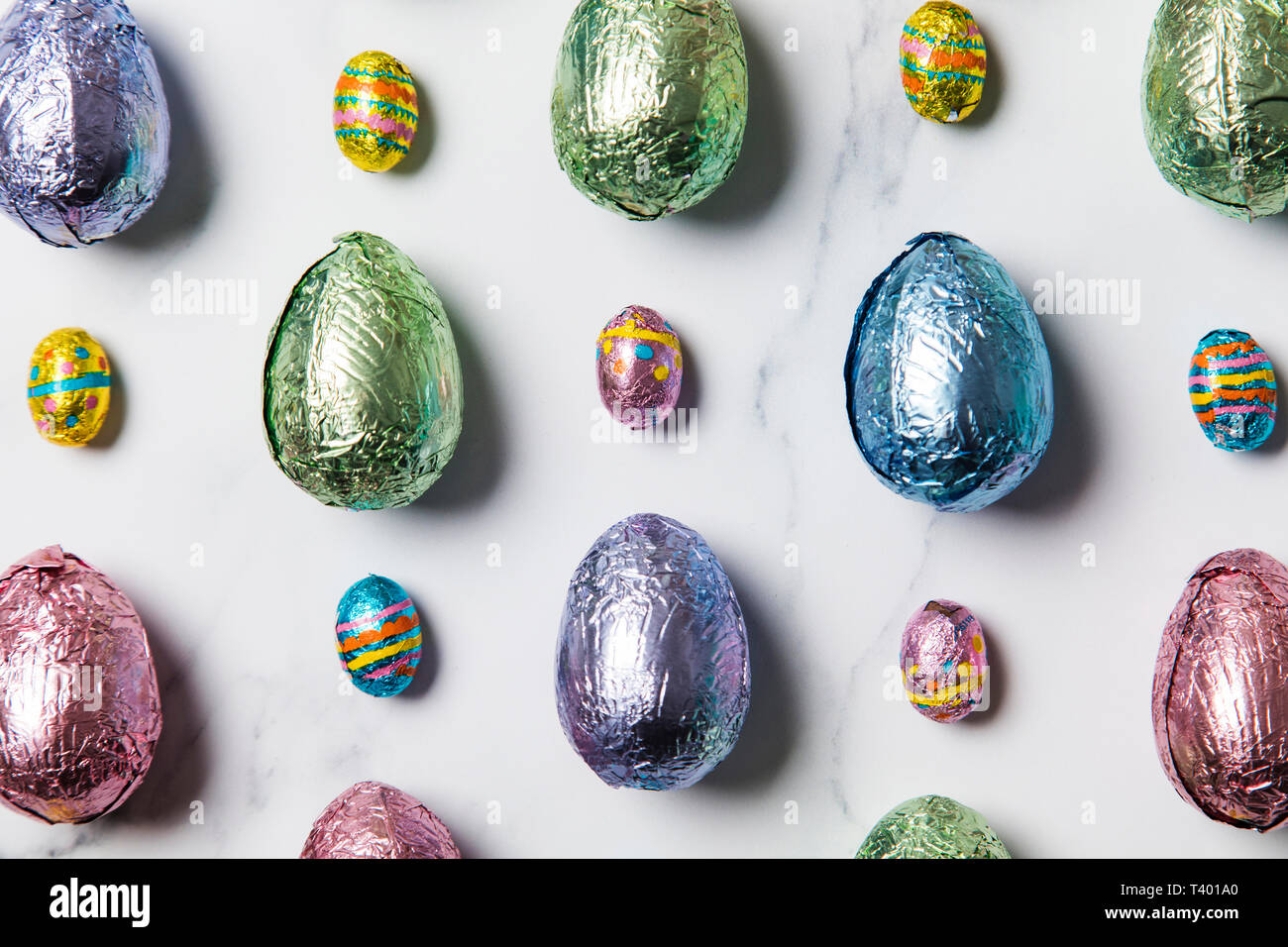Easter egg chocolate treats wrapped in shiny coloured foil on marble ...