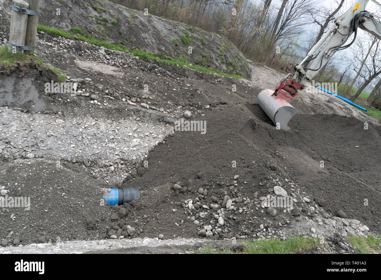laying large industrial water pipes in an earth and dirt ditch for ...
