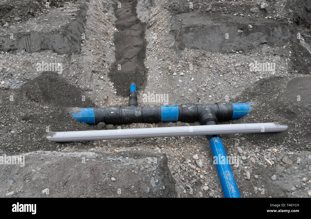 laying large industrial water pipes in an earth and dirt ditch for ...