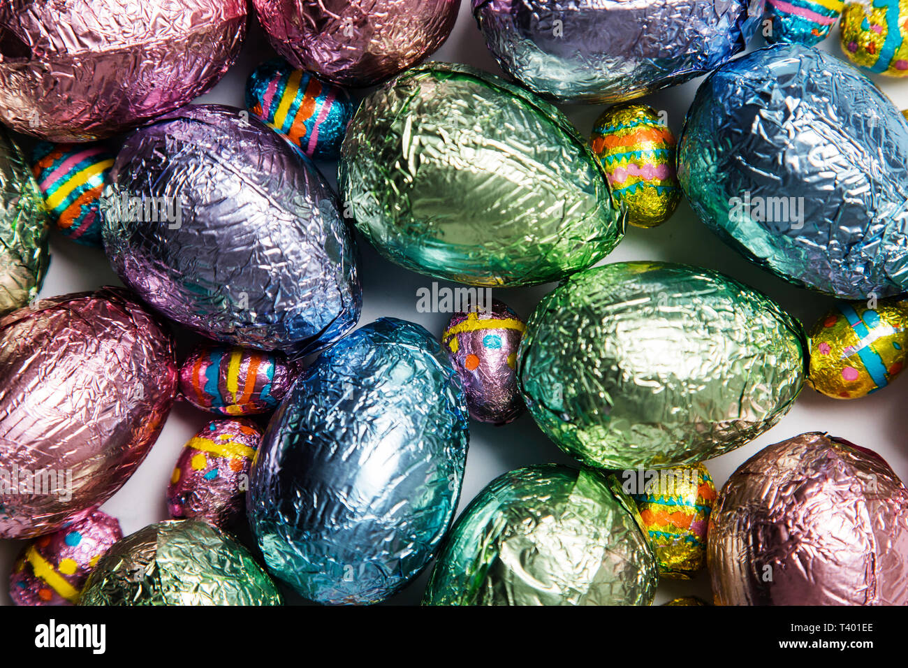 Easter egg chocolate treats wrapped in shiny coloured foil on marble ...
