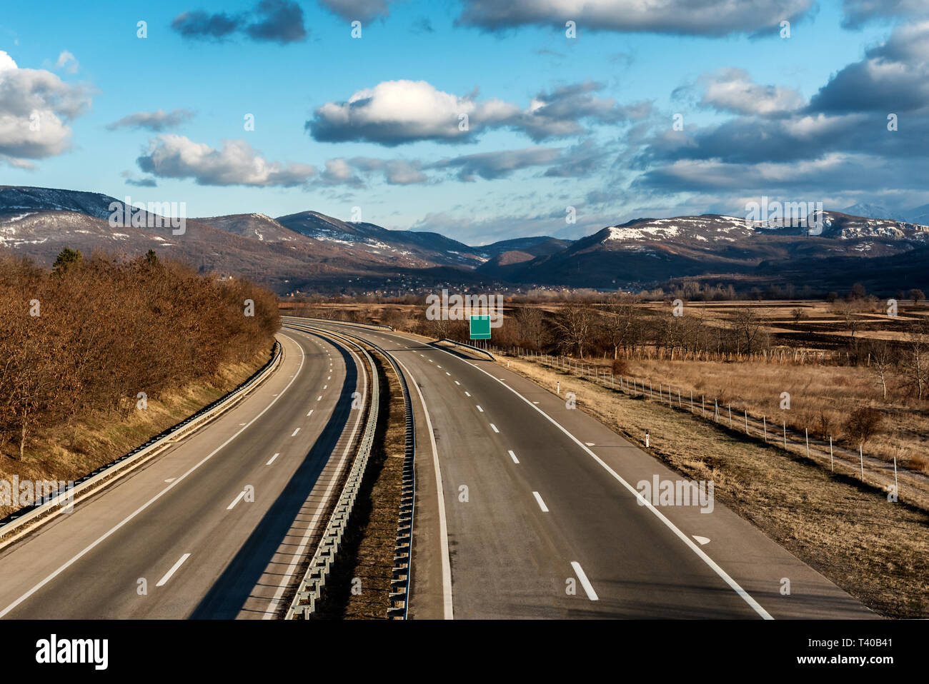 Two line wide highway curve on a summer day leading to the mountains ...