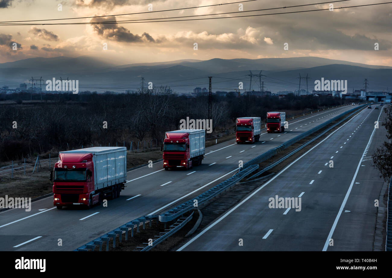 Caravan or convoy of lorry trucks on country highway under a beautiful ...