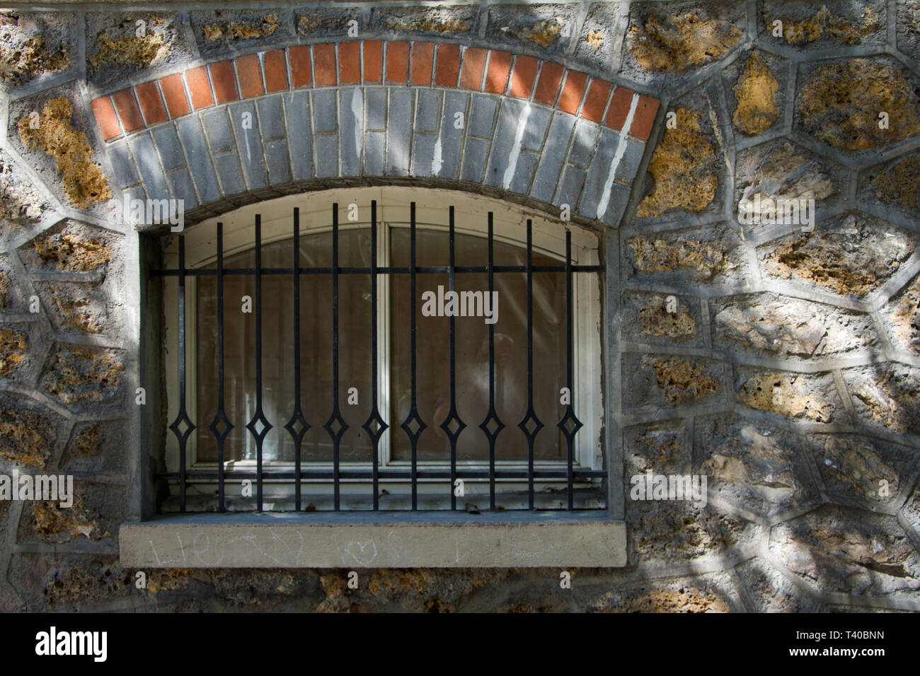 Arch shaped ground window covered with lattice on a brick wall Paris ...