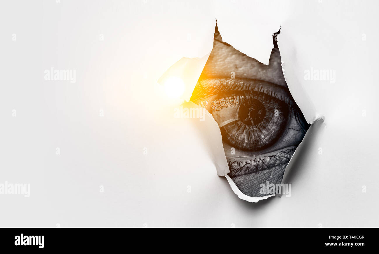 Eye in a hole of torn paper Stock Photo - Alamy