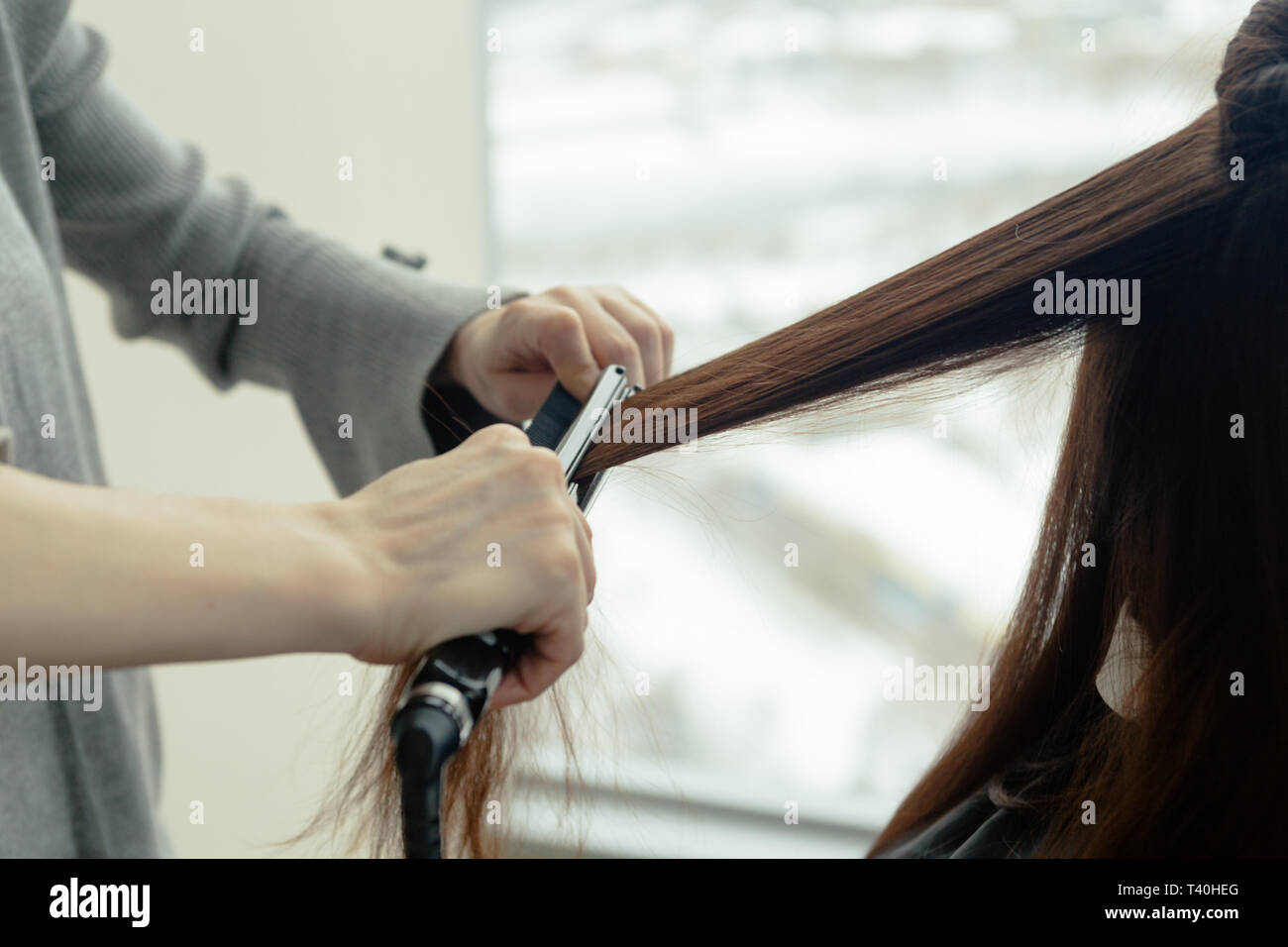 Hairdresser straightening models hair in a beauty salon Stock Photo - Alamy