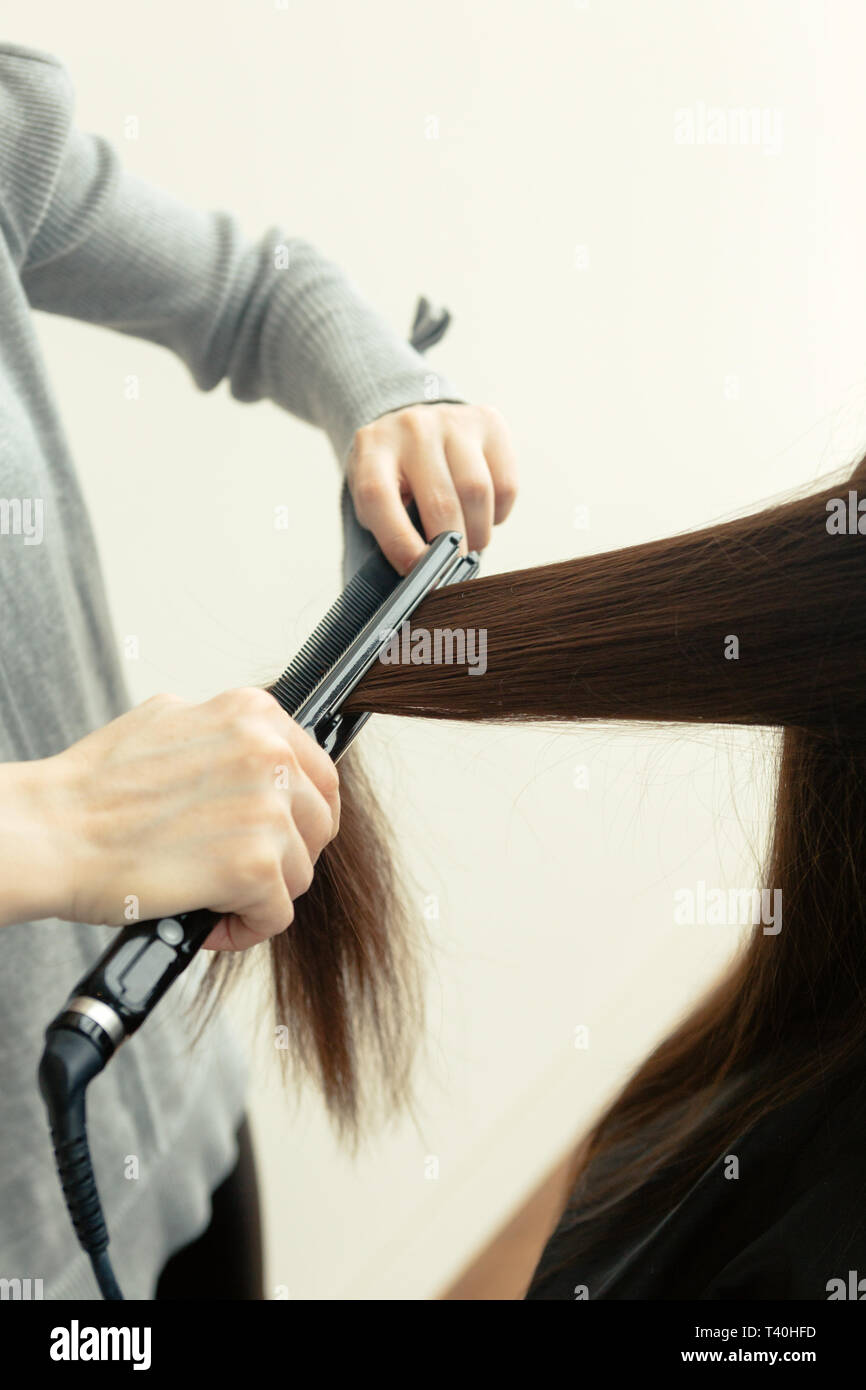 Hairdresser straightening models hair in a beauty salon Stock Photo - Alamy