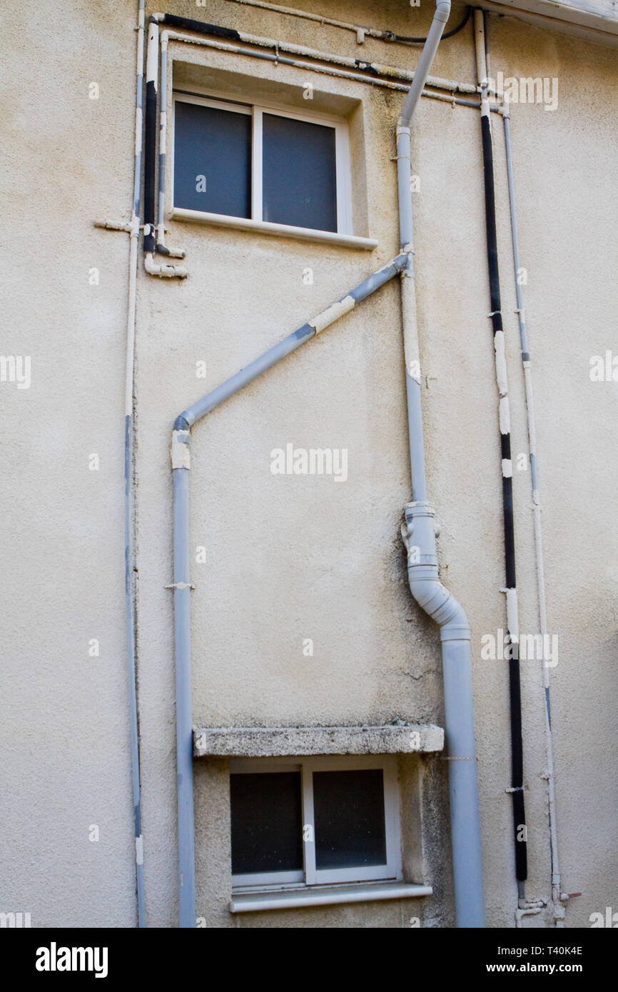 Windows and exterior pipes of an old apartment building Stock Photo - Alamy