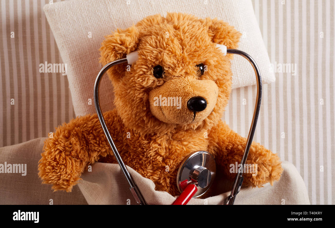 Cute plush teddy bear using a stethoscope to listen to its own heart as ...