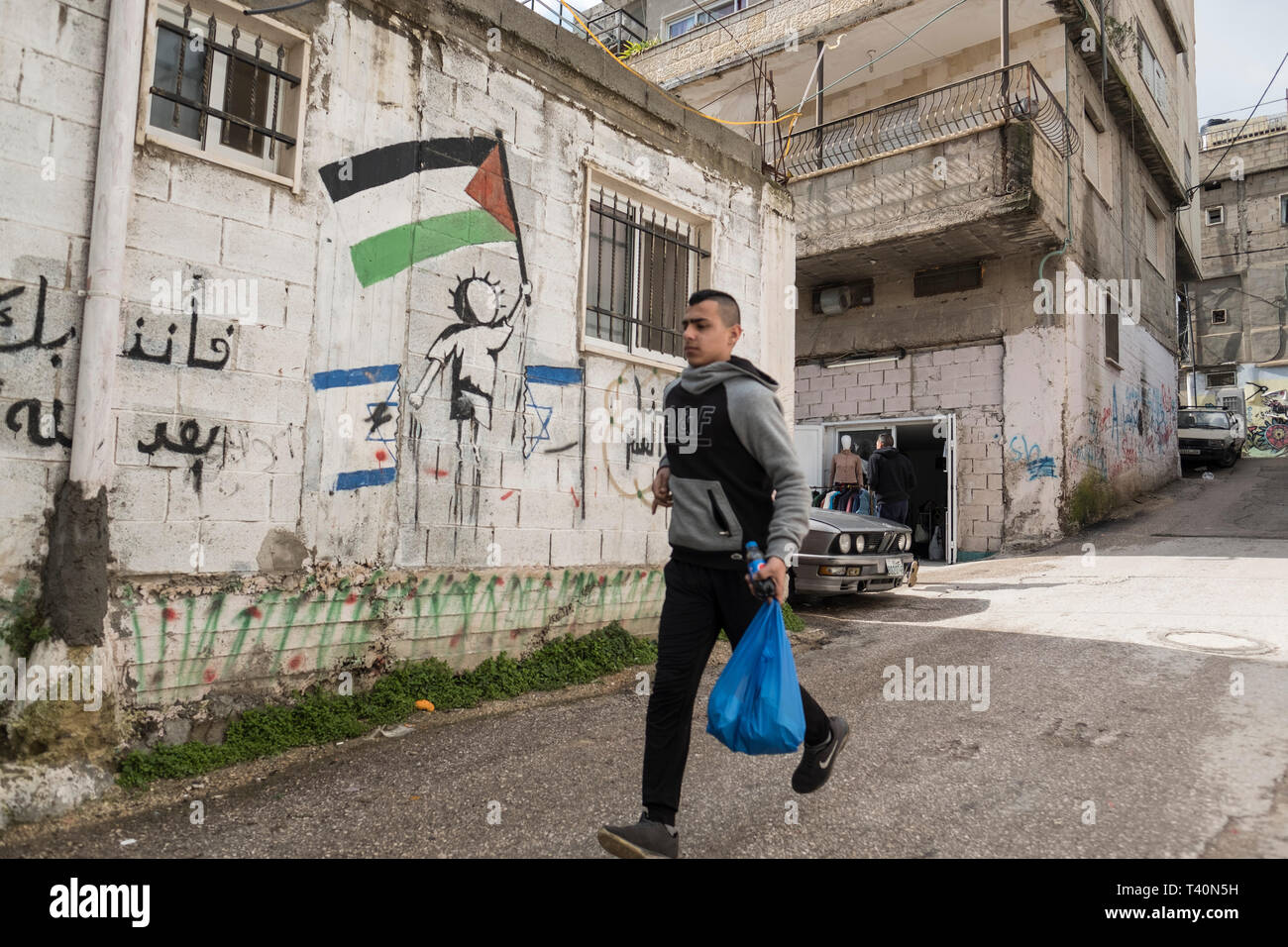 A Palestinian teenager runs past resistance paintings on the walls in ...