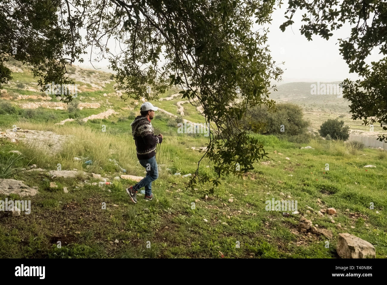 A Palestinian teenager prepares a sling shot to throw stones at the ...