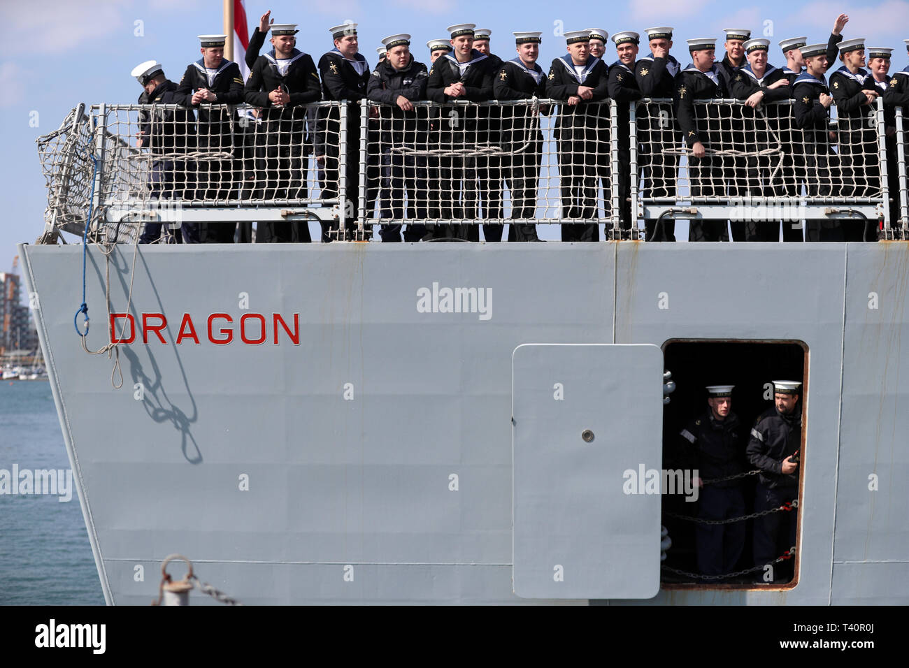 Crew members onboard HMS Dragon wave to the waiting crowd as she ...