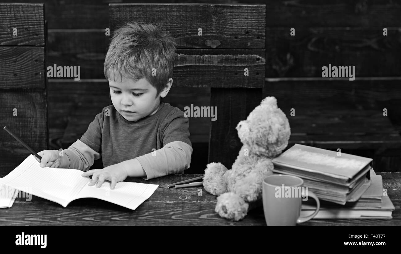 Concentrated kid writing in copybook. Preschool boy sitting at desk ...