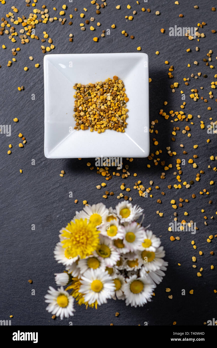 small bowl of pollen grains with small bunch of flowers out of focus ...