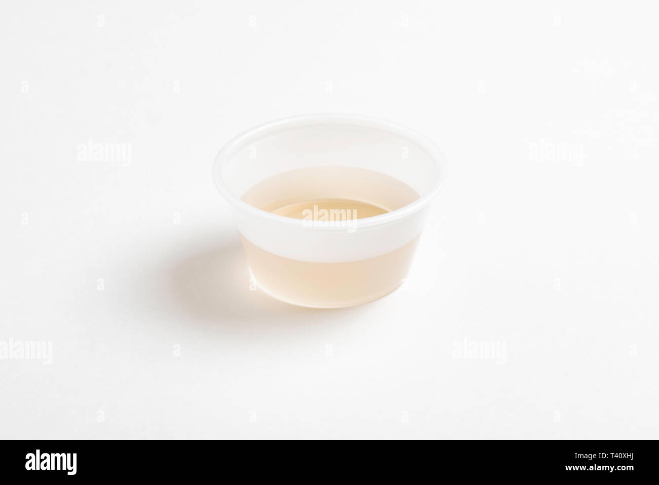 A urine sample in a plastic container with a reagent strip set on a ...