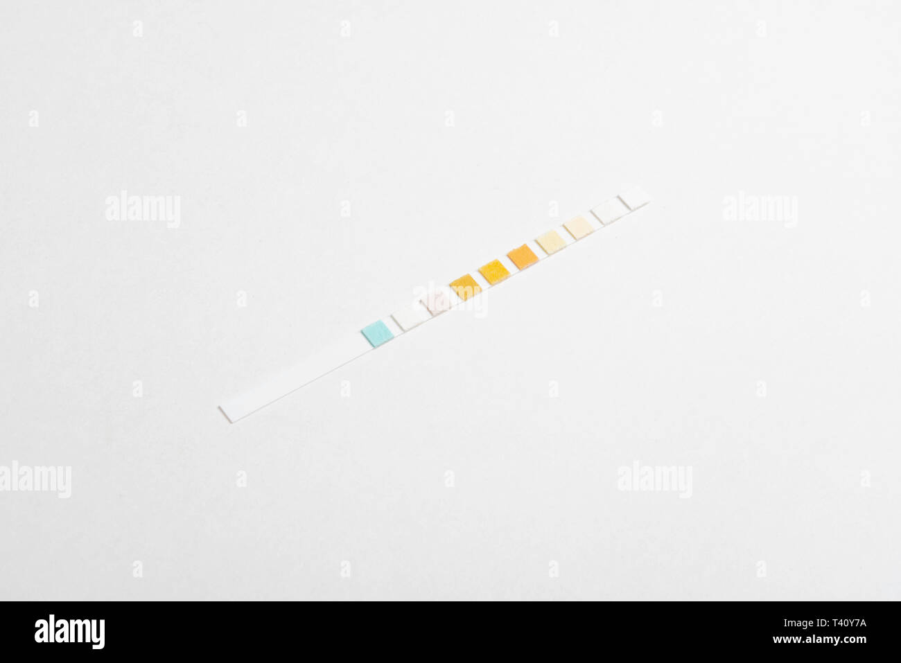 A single piece of medical grade urine reagent test strip set on a white ...