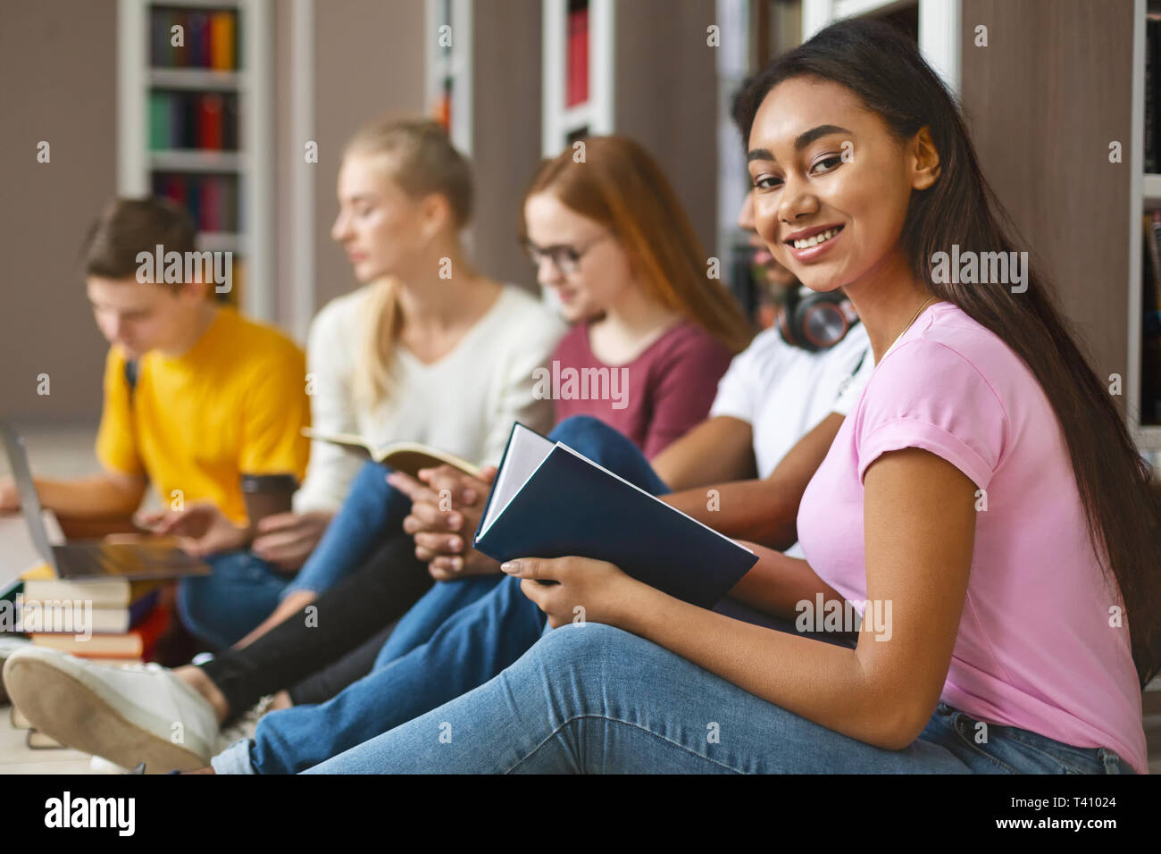 Group of diverse classmates sitting on floor at library Stock Photo - Alamy