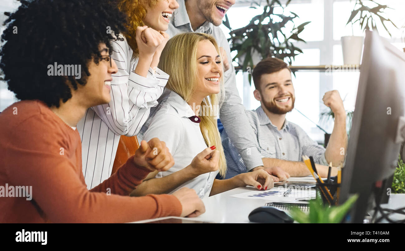 Cheerful young team celebrating success, looking at computer Stock ...
