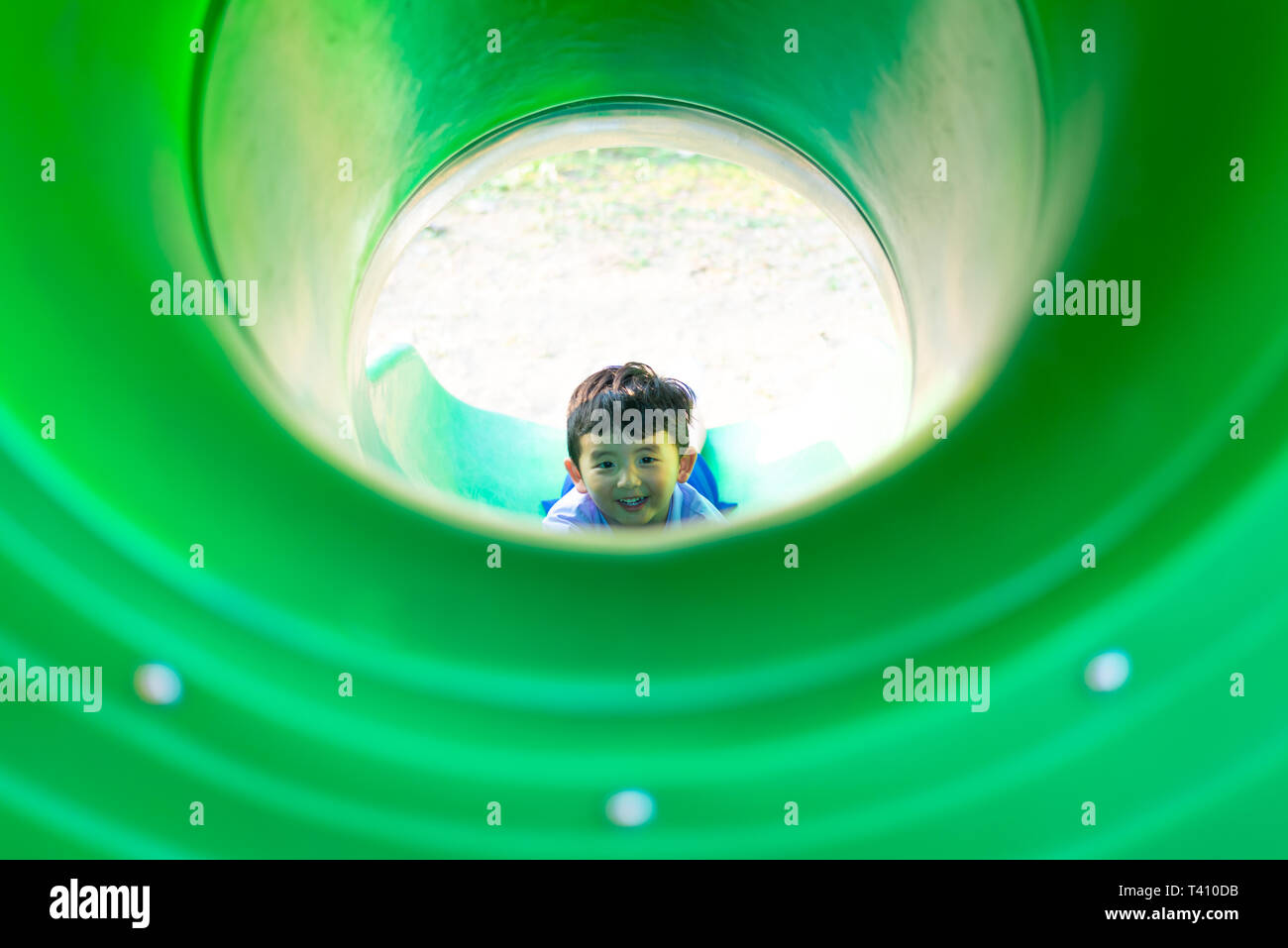 Little Asian kid climbing up the slide at the playground under the ...