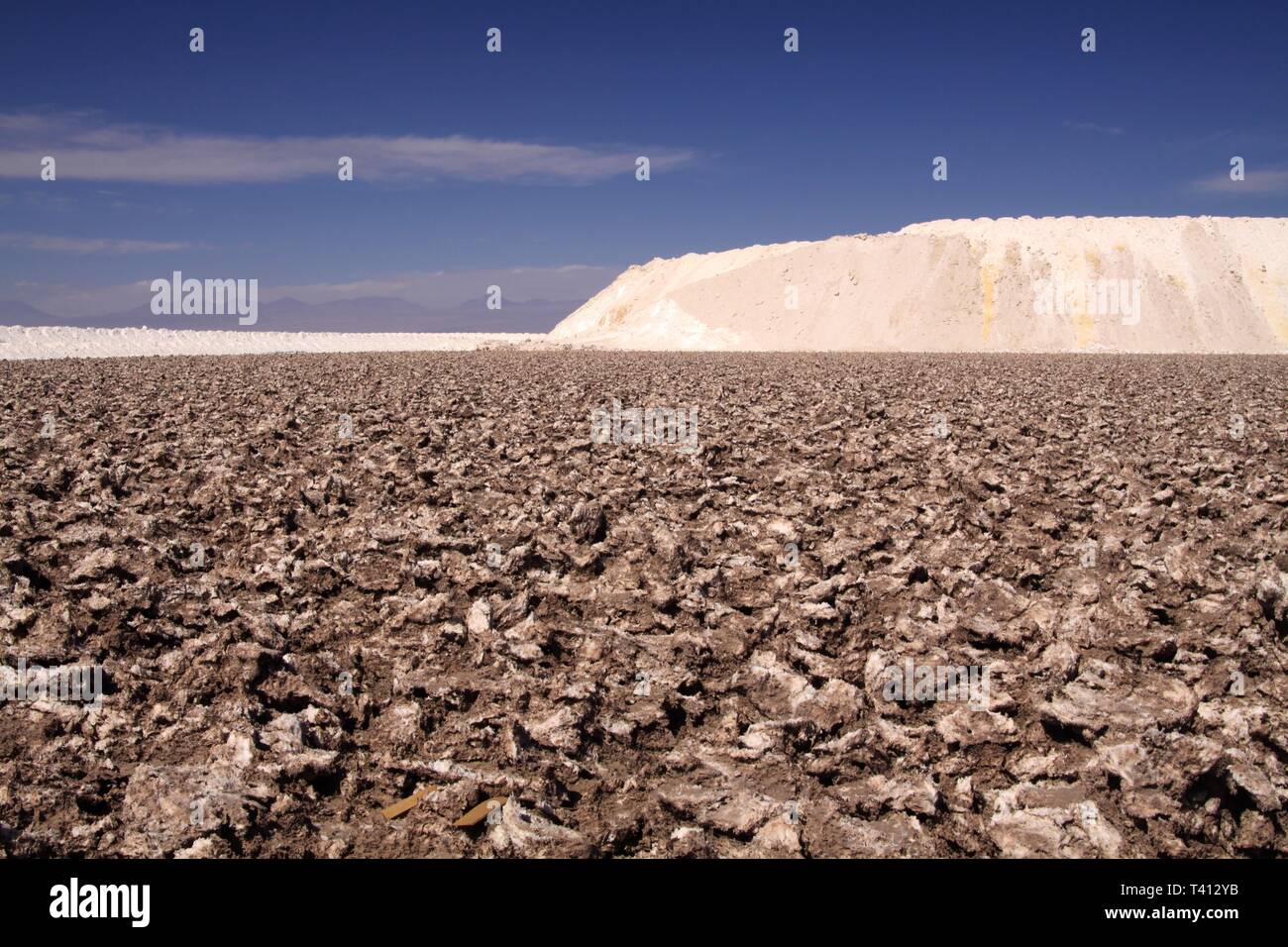View over barren rugged ground on isolated white hill contrasting with ...