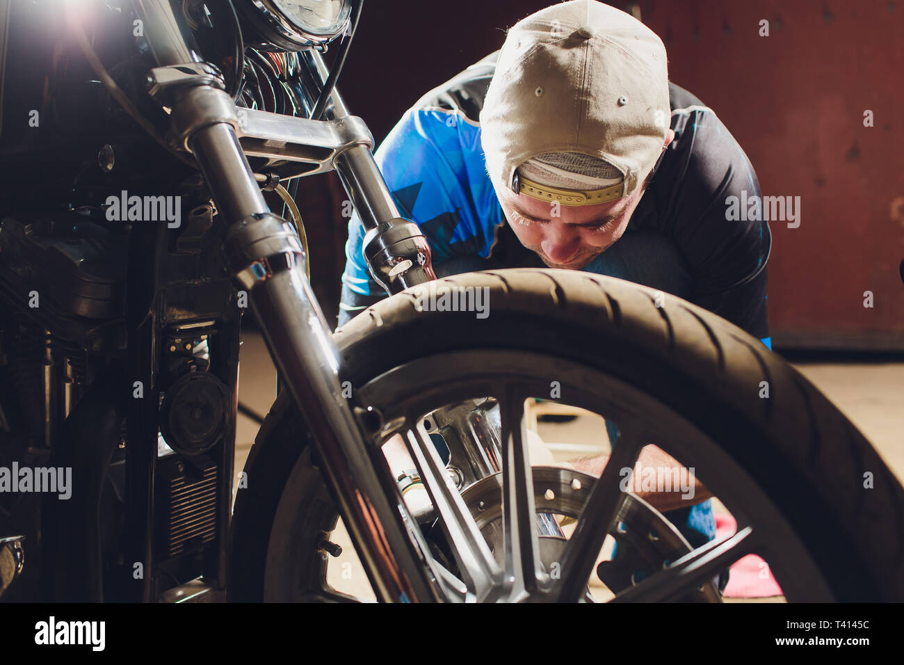 Man fixing bike. Confident young man repairing motorcycle near his ...