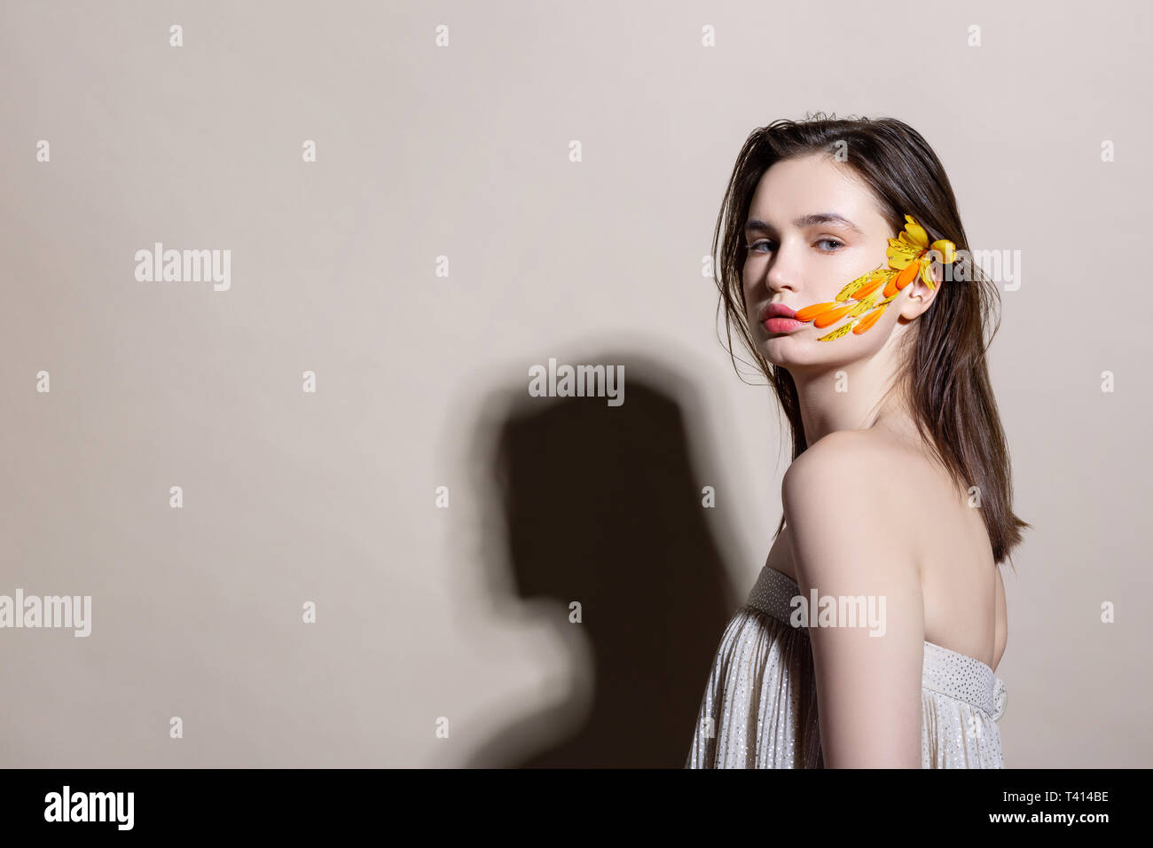 Model posing in open shoulder dress having feathers on face Stock Photo ...