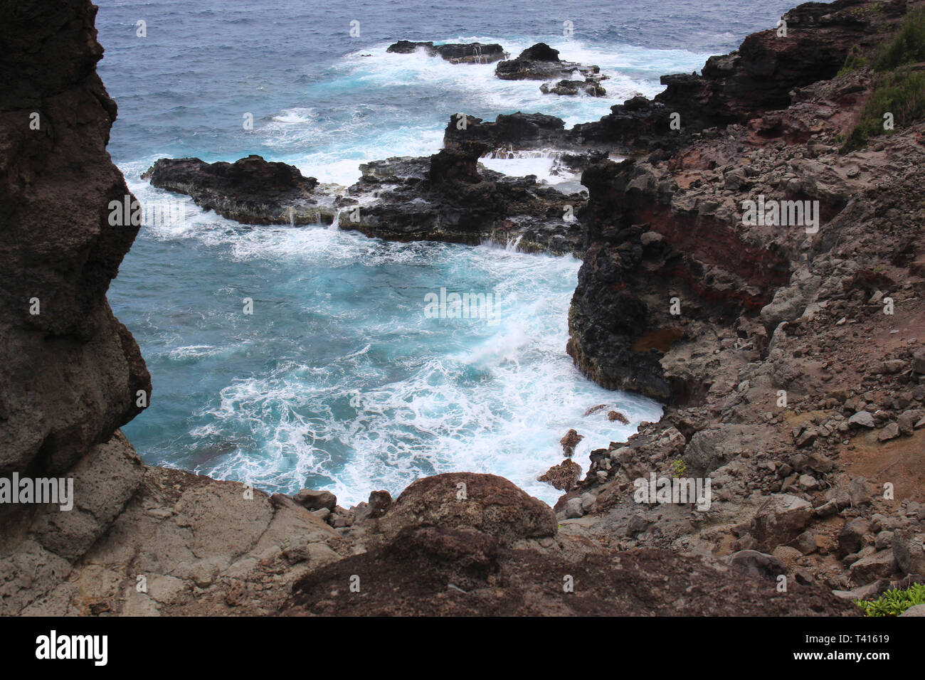 The Pacific Ocean, in varying shades of blue, and the volcanic cliff ...