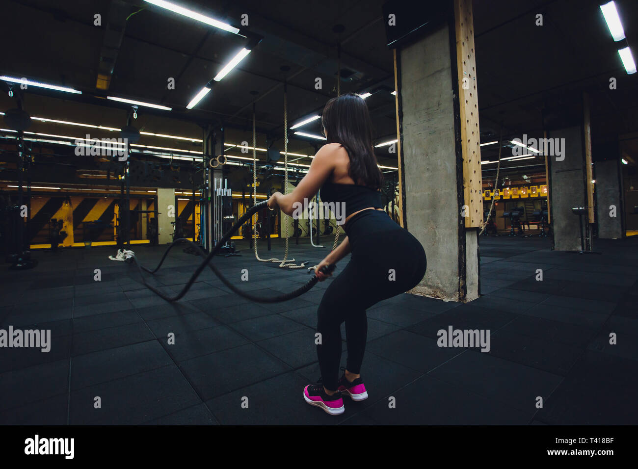 Woman training with battle ropes in gym, doing intense hard training ...