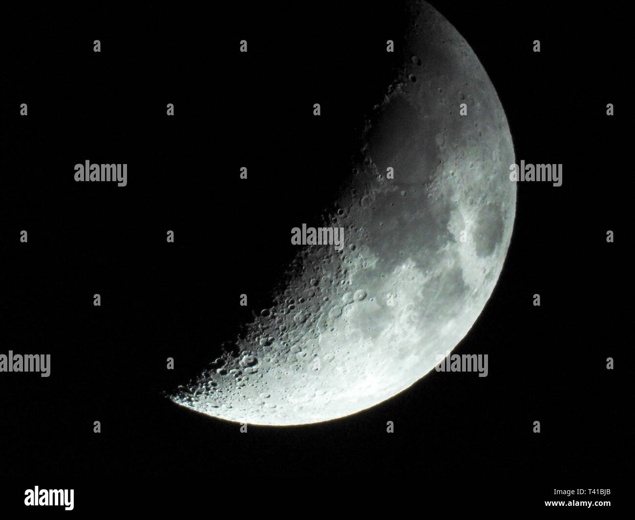 a crescent moon with clear visibility reveals many craters on the ...