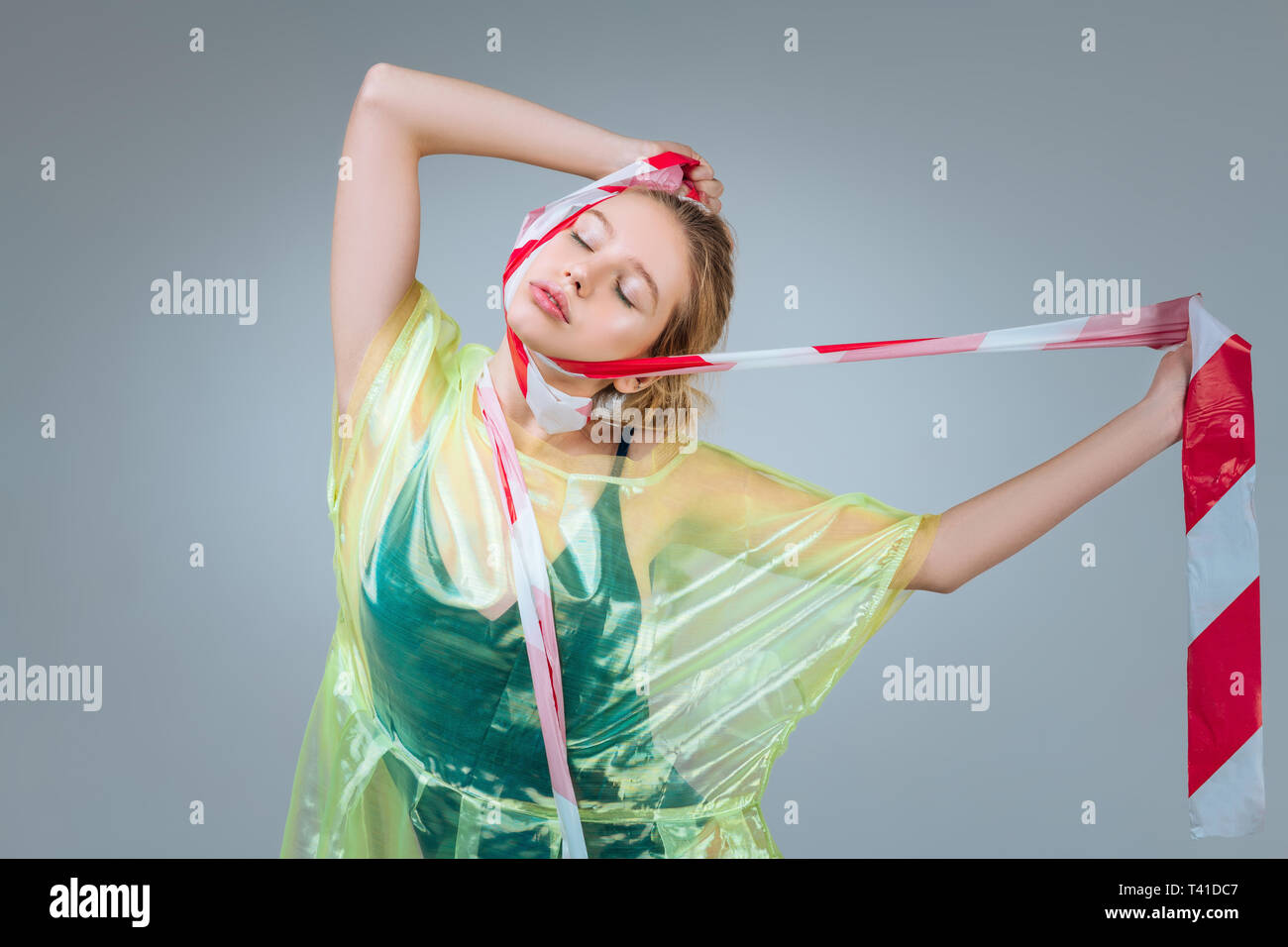 Closing eyes. Skinny model wearing plastic clothes closing eyes while ...