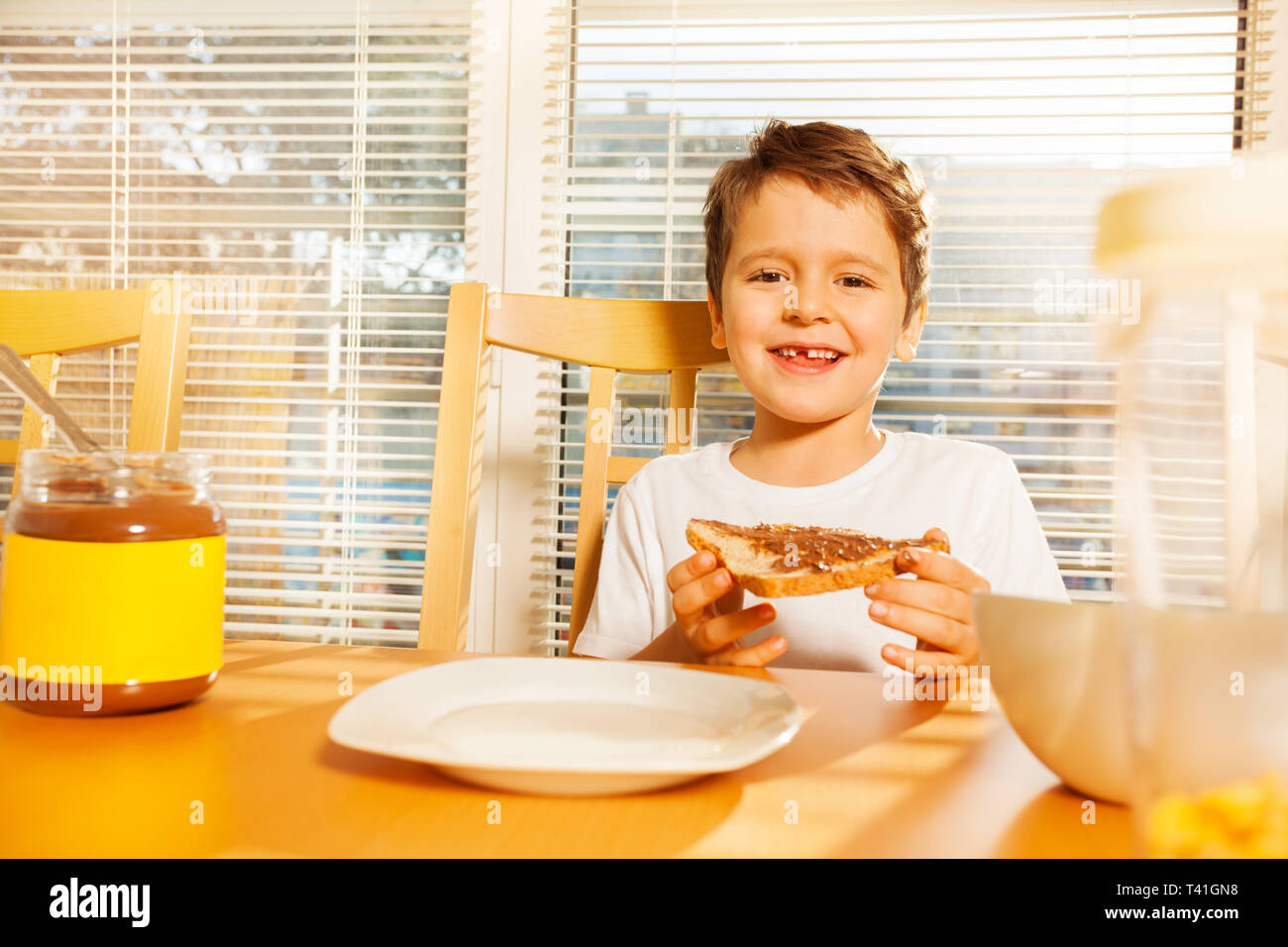Happy boy eating toast with chocolate spread Stock Photo - Alamy