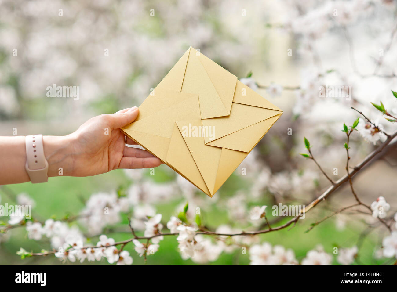 Close-up woman hand holding invitation card golden color, front view ...
