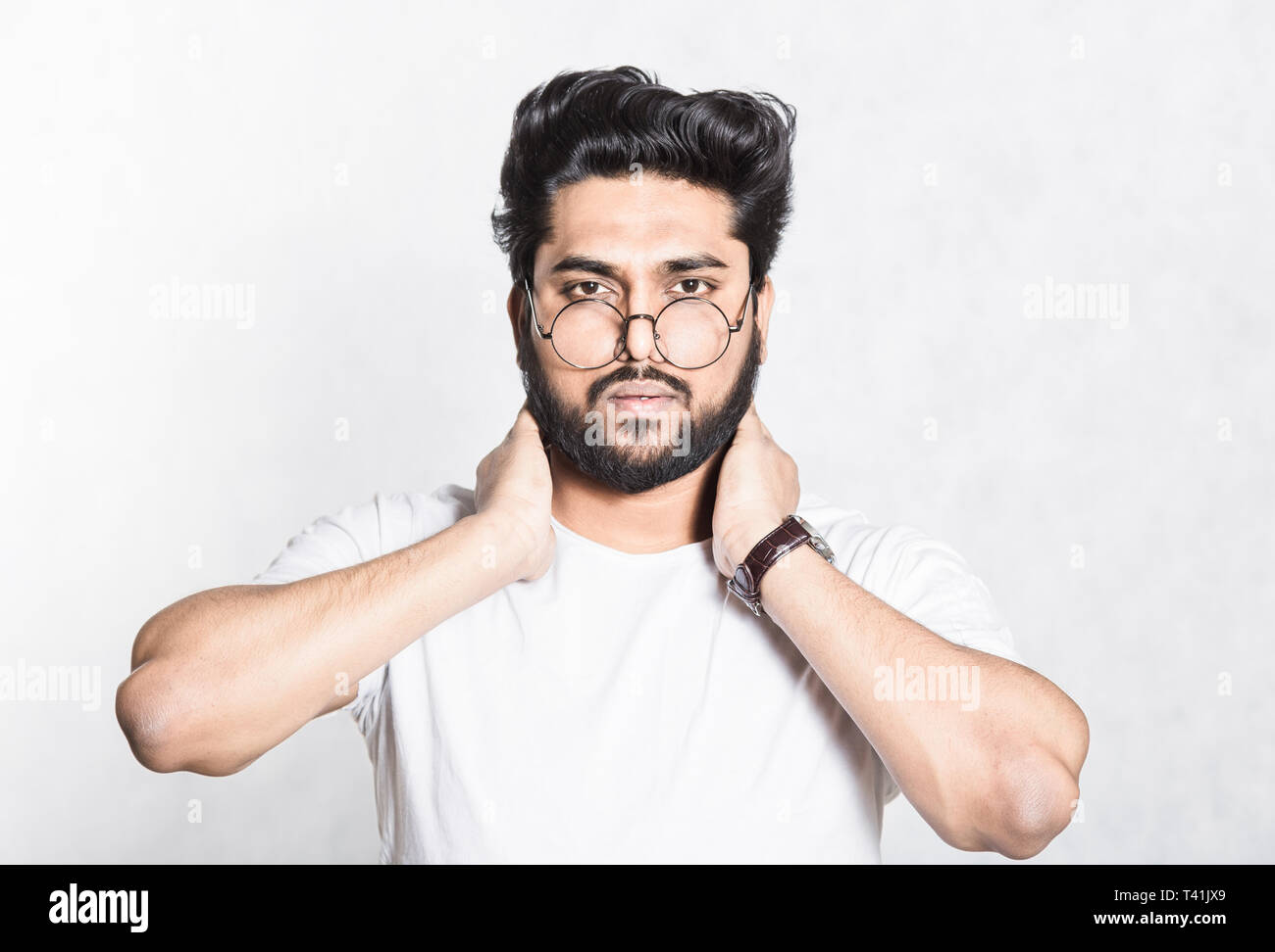 Attractive young man keeps hand on neck, tries to relieve muscle ...