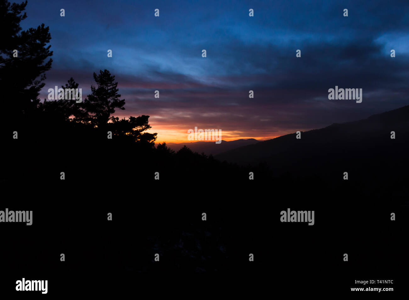 Nice sunset between mountains and forests Stock Photo - Alamy