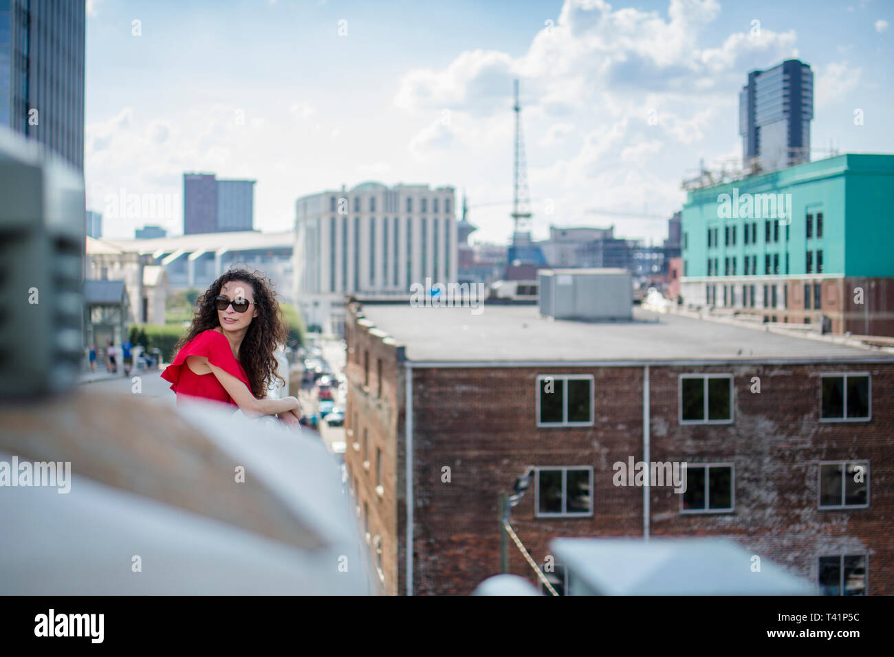 a windblown woman in a red dress smiles against a city backdrop Stock ...