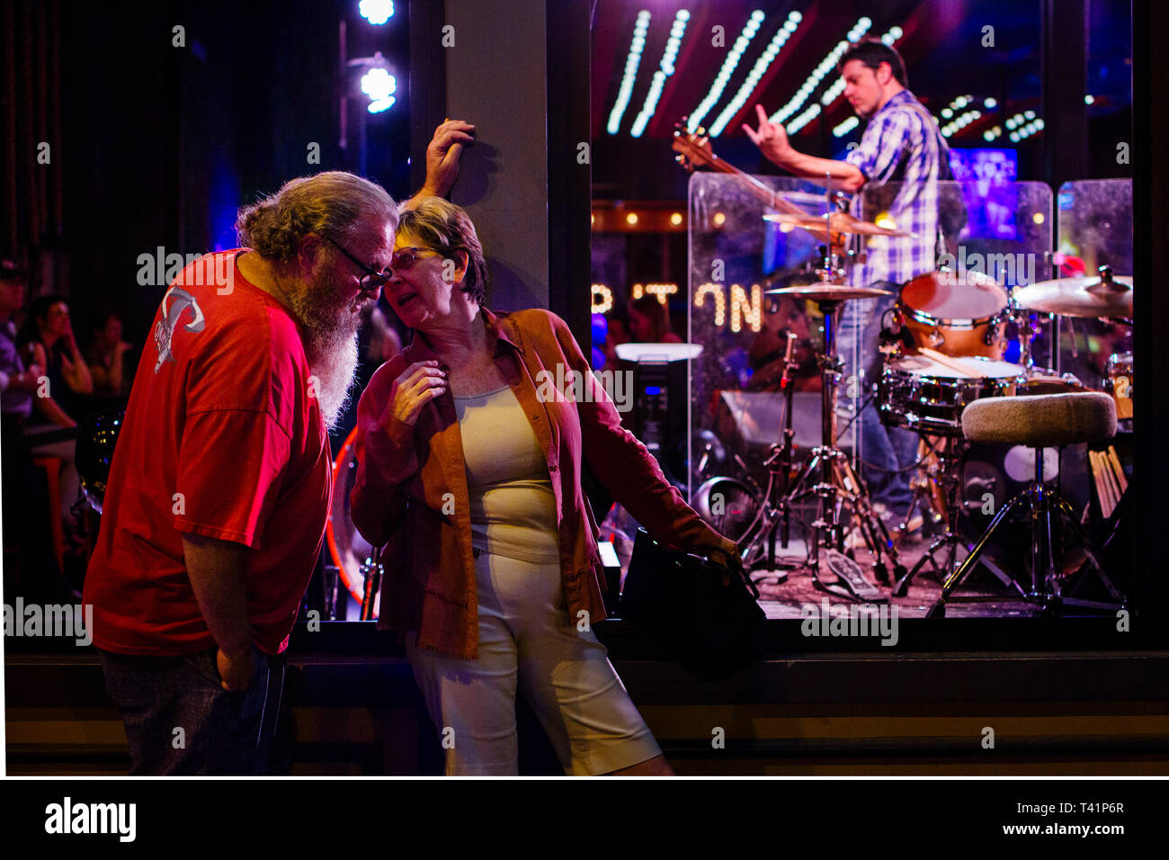 an elderly couple lean close together against a doorway outside a club ...