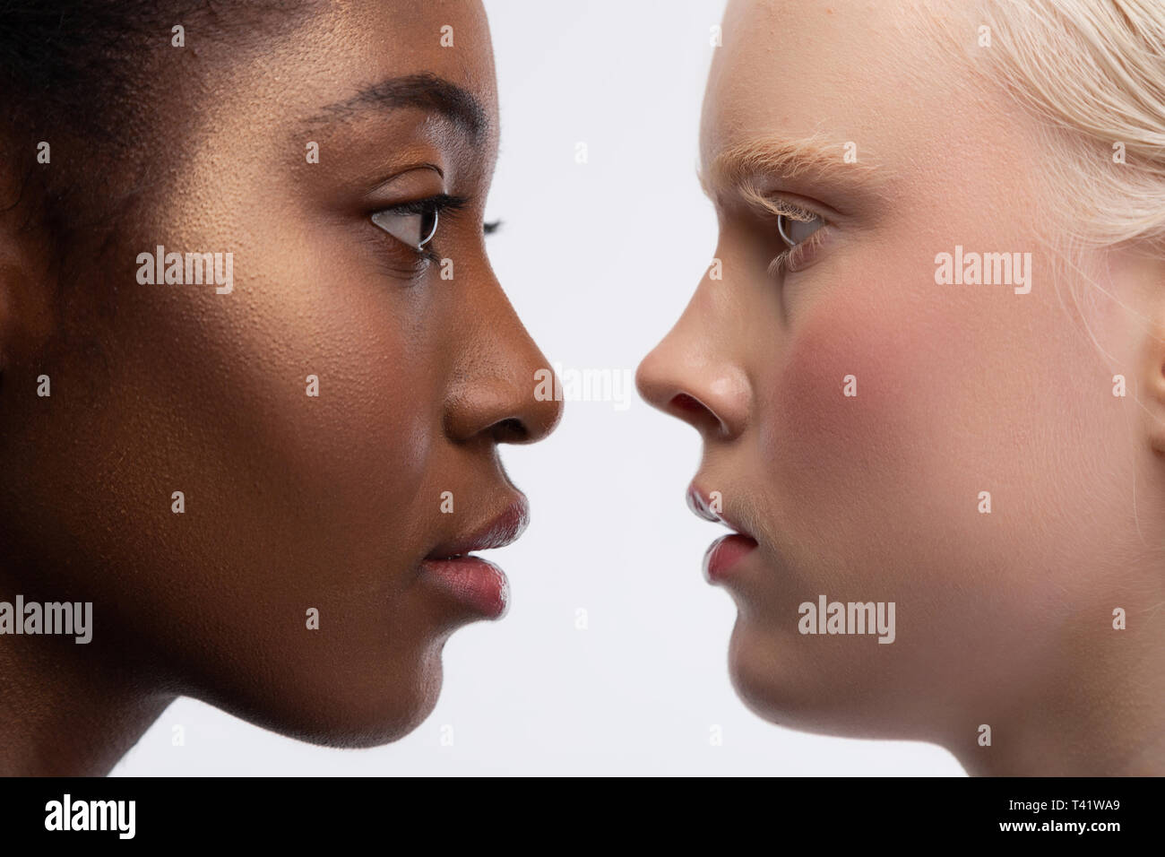 Looking into eyes. Two young multinational women with different skin ...