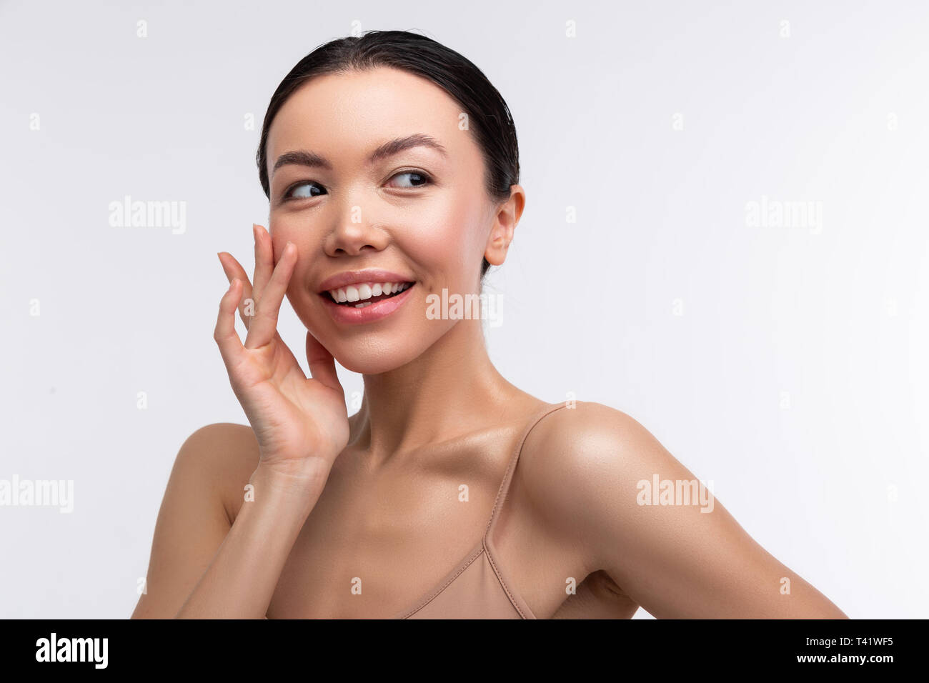 Touching face. Appealing young dark-haired woman with open shoulders ...