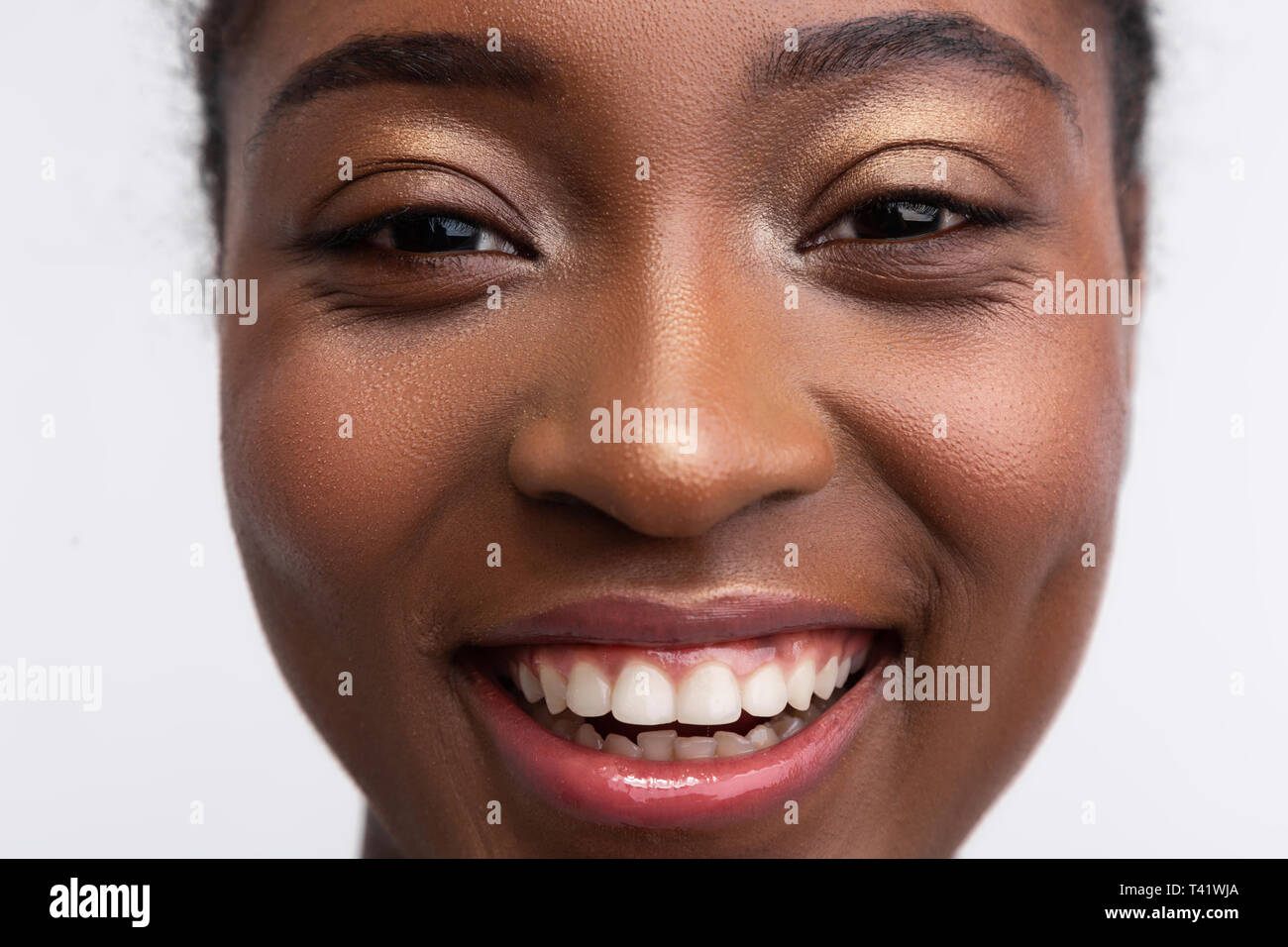 Broad smile. Beaming happy dark-skinned woman smiling broadly while ...