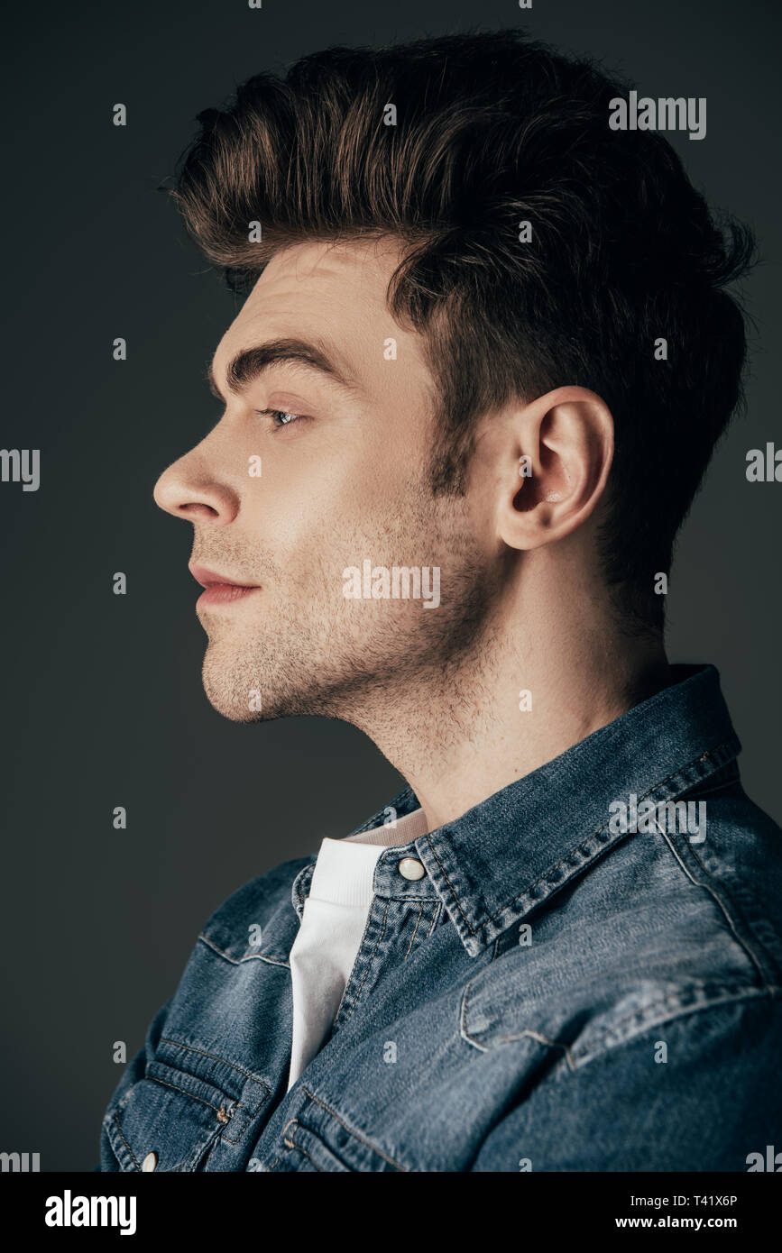 side view of handsome and brunette man in denim shirt isolated on black ...