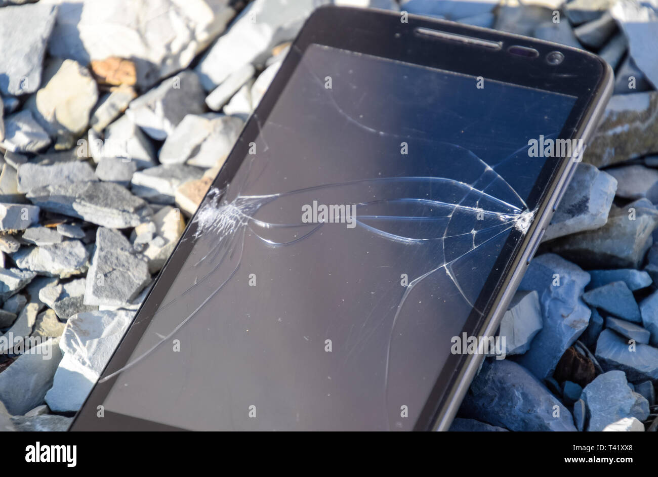 Frustrated phone on the rocks. Glass shattered on rocks on a smartphone ...