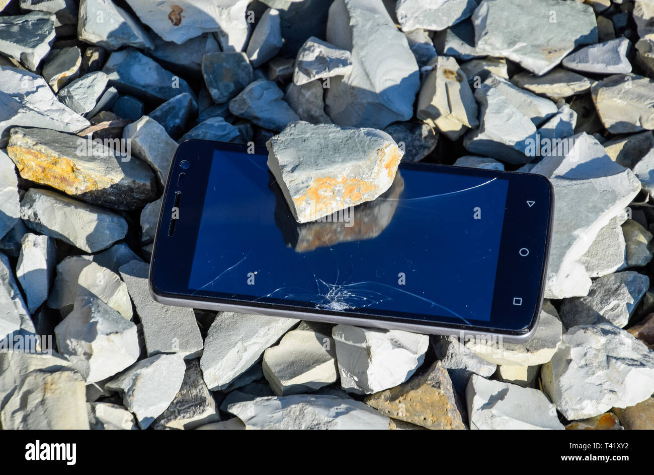 Frustrated phone on the rocks. Glass shattered on rocks on a smartphone ...