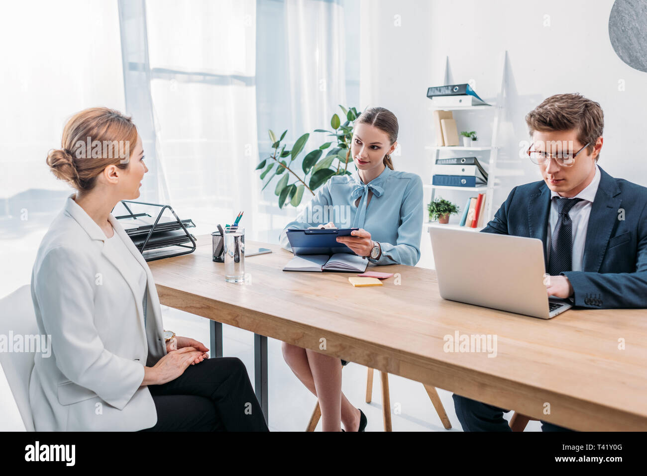 woman talking with recruiter holding clipboard while coworker using ...